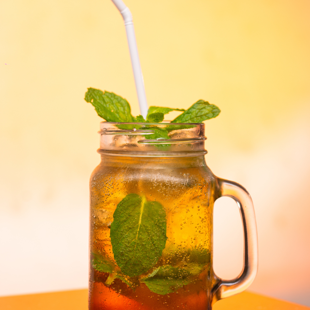 glass with a manuka honey cocktail mint leaves and a straw